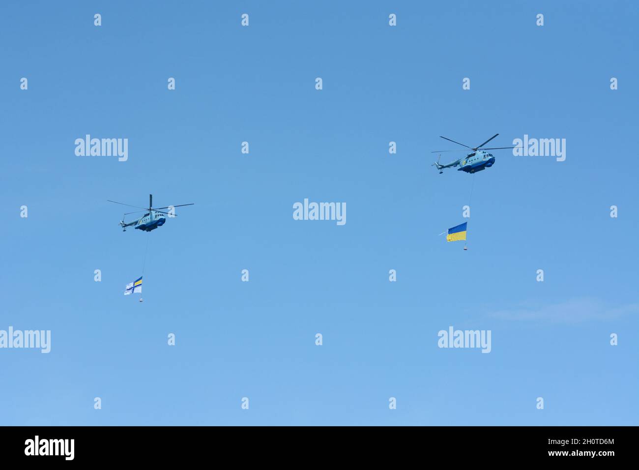 Military helicopters flying in a blue sky with flags. Military parade ...