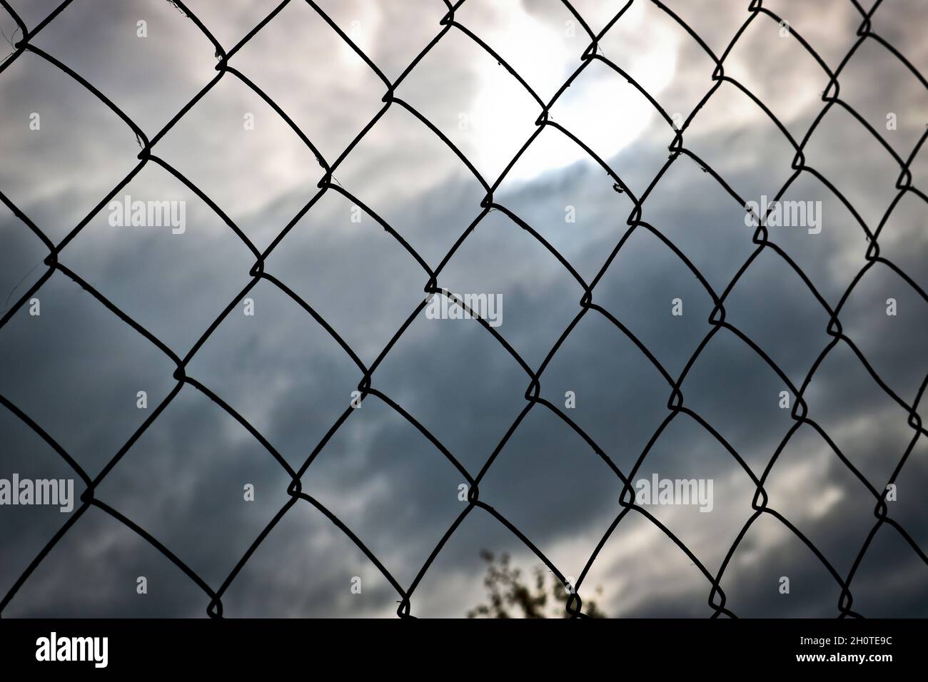 Metal mesh-netting against the background of a stormy sky. Disturbing ...