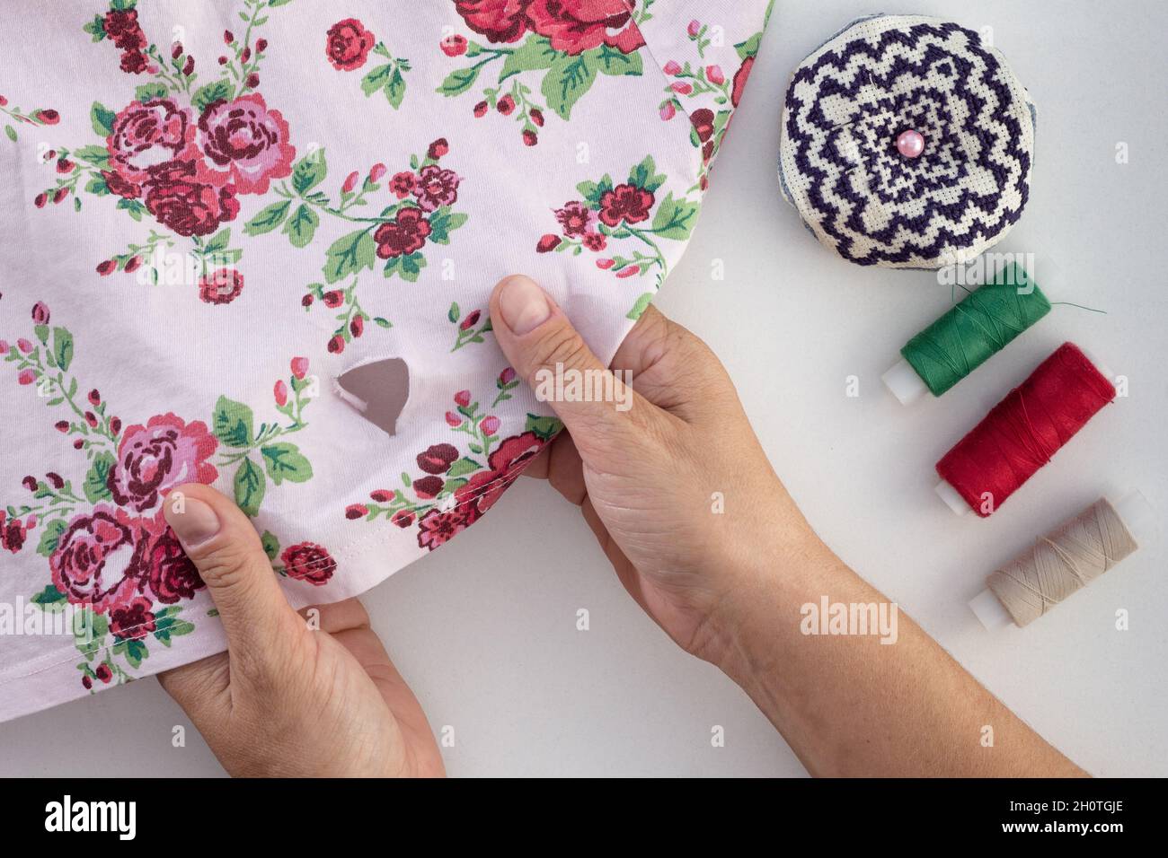 Woman hand holding torn cloth showing hole on white background with ...
