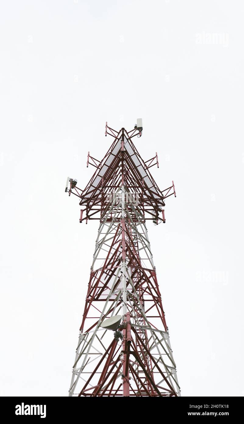 Vertical shot of the tip of white and red cell tower in the fog under ...
