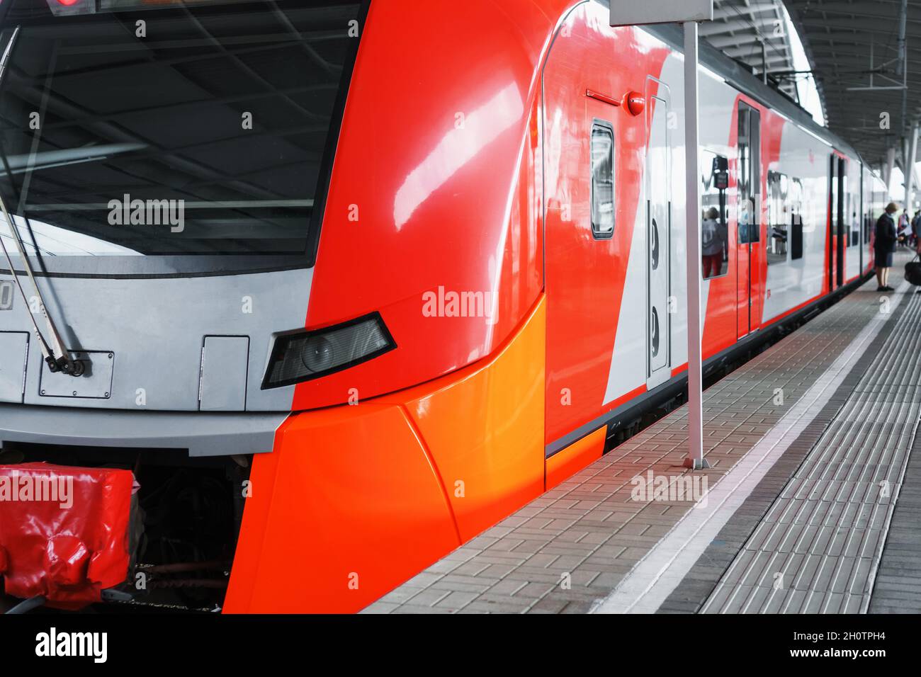 A high-speed red-gray electric train is standing on the platform. High ...