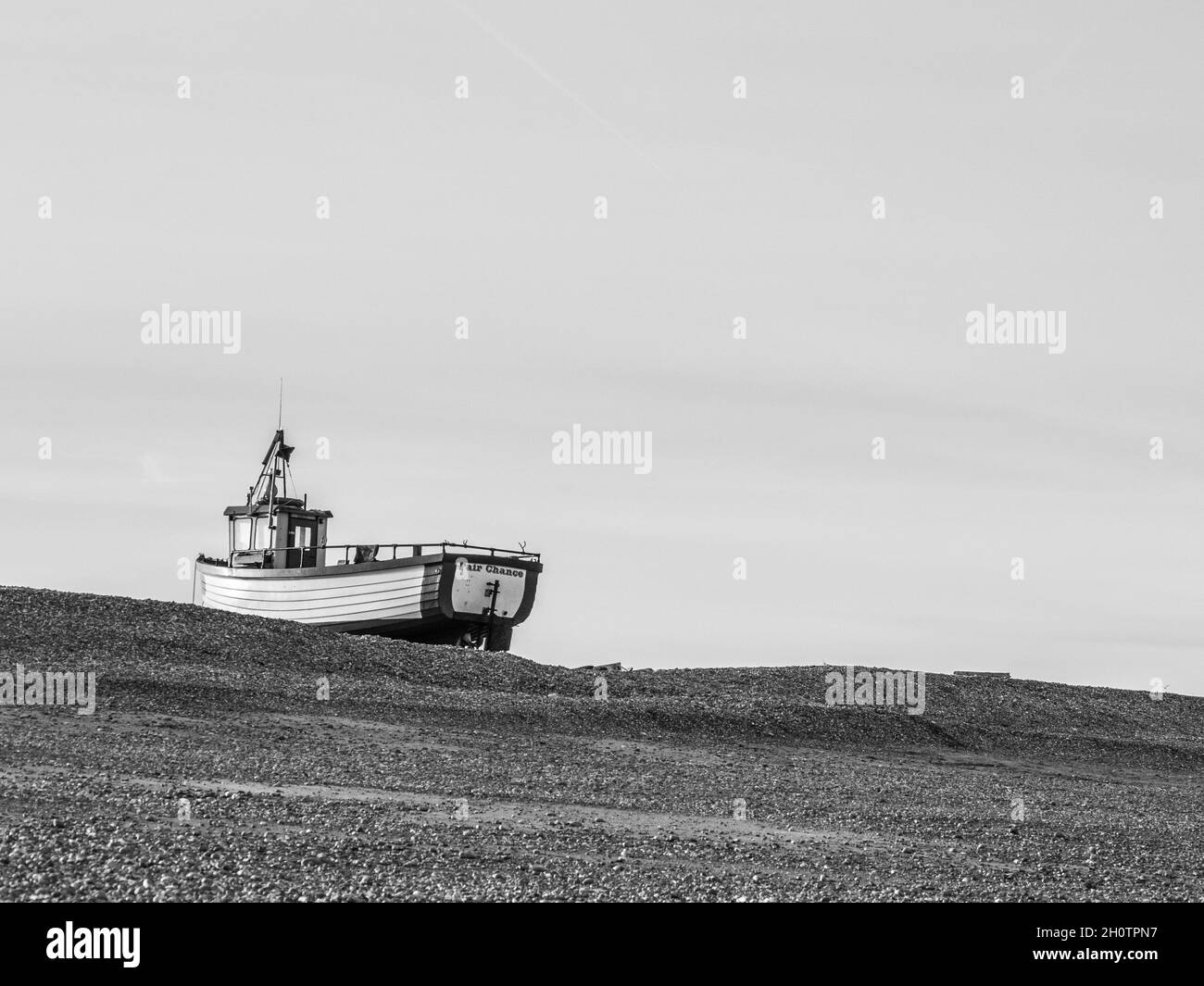 White and blue fishing boat park on a rail track at a pebble beach at ...