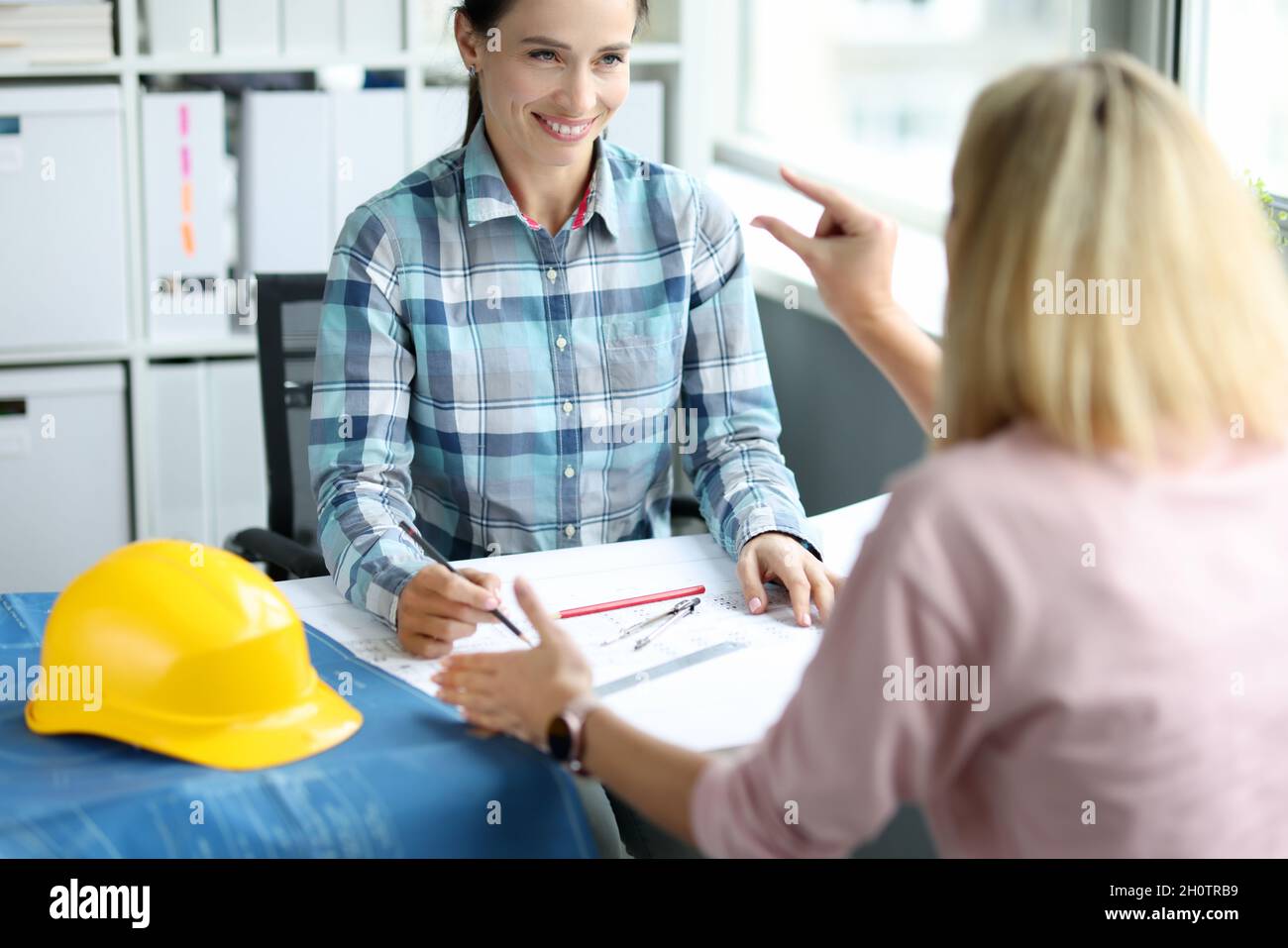 Woman designer architect makes project of house with client in office ...