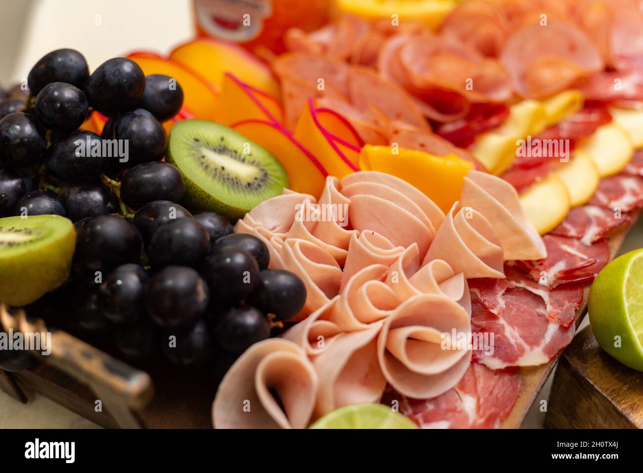 Detail of a cold cuts board on the table, with salami, cheese, fruits ...