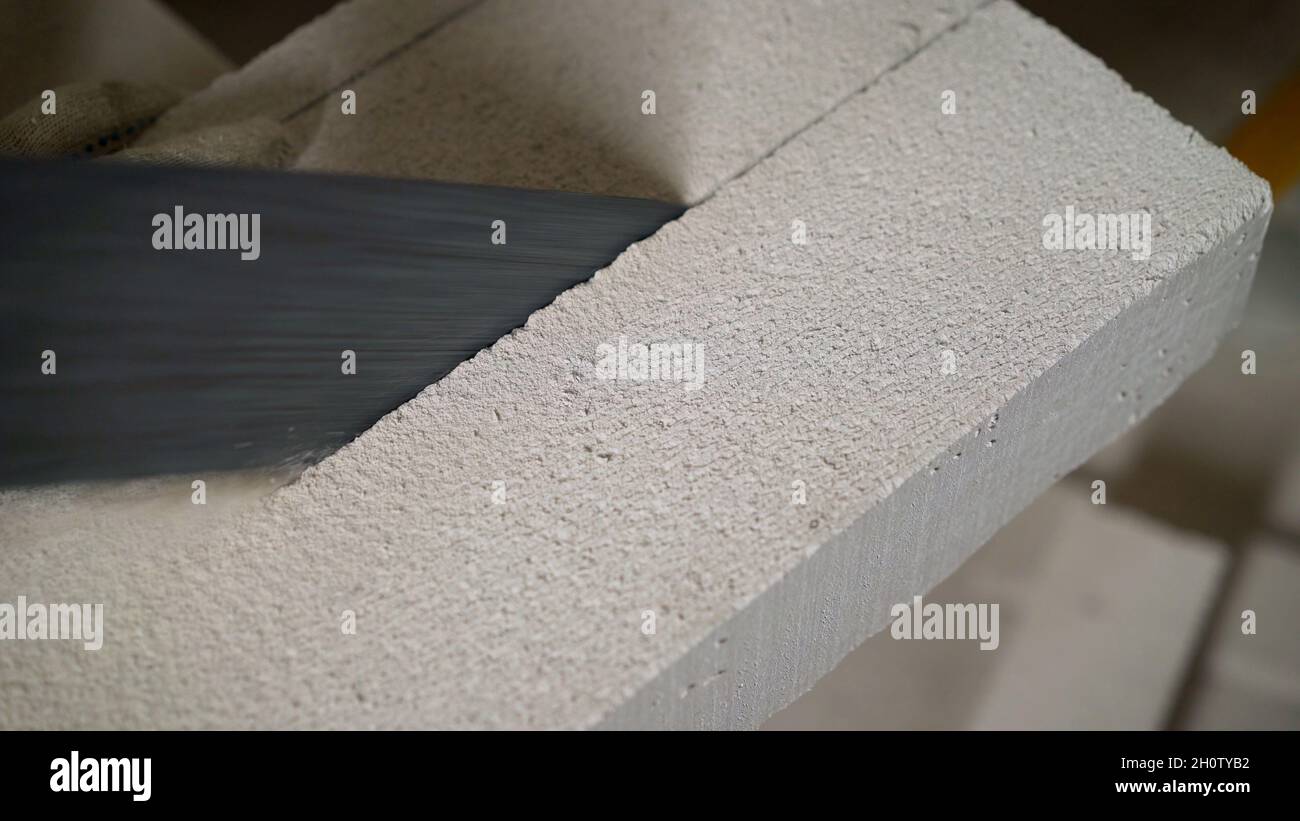 A worker cuts an aerated concrete block. Worker cutting construction ...