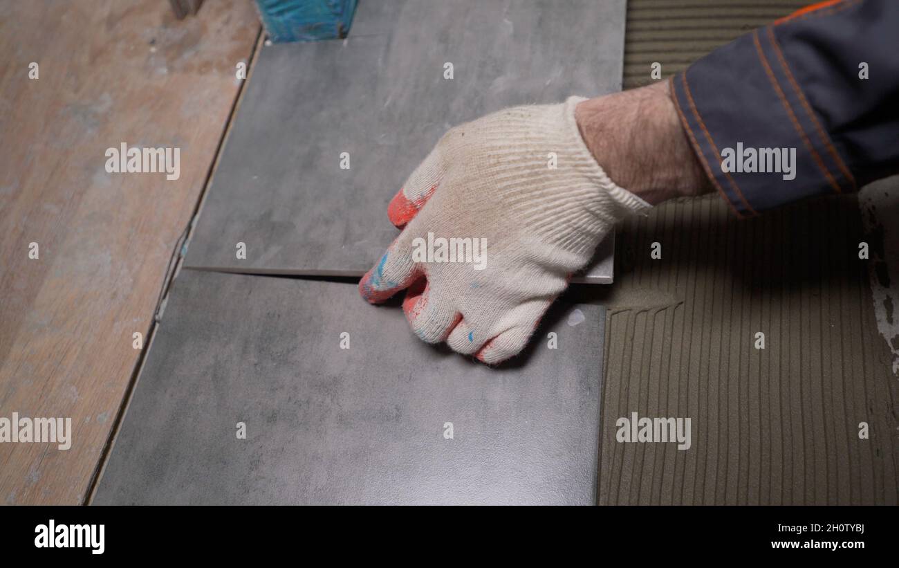 A worker smears ceramic tiles for laying. Laying ceramic tiles on the ...