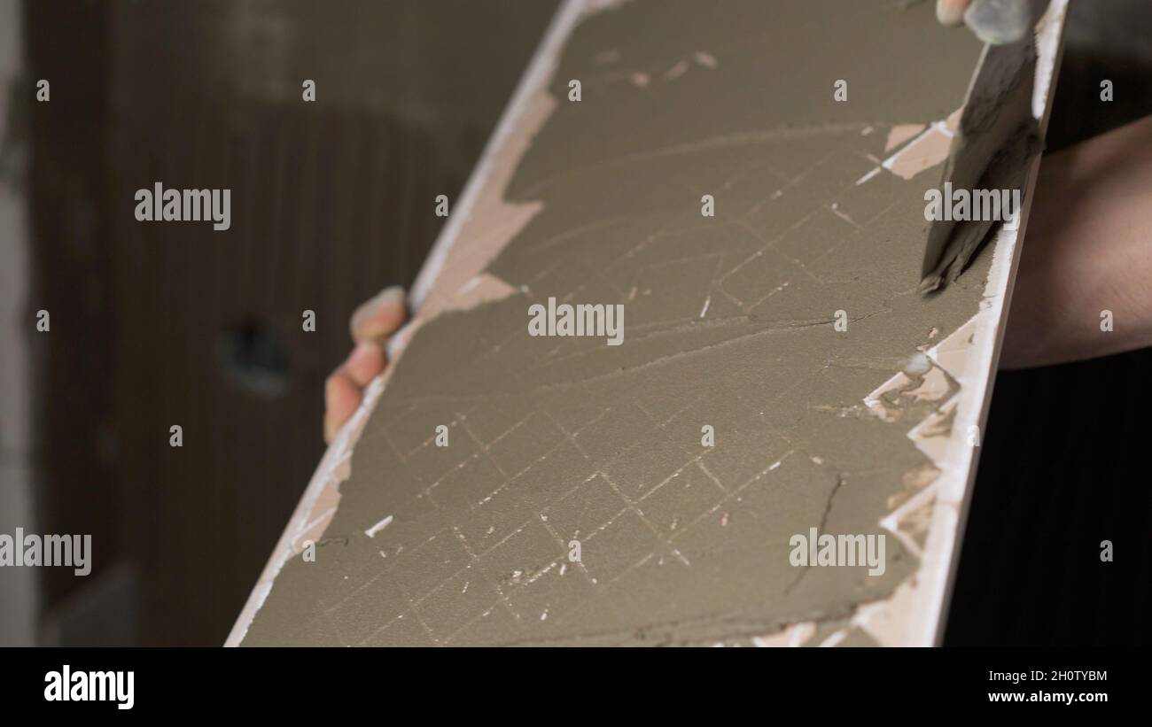 A worker smears ceramic tiles for laying. Laying ceramic tiles on the ...