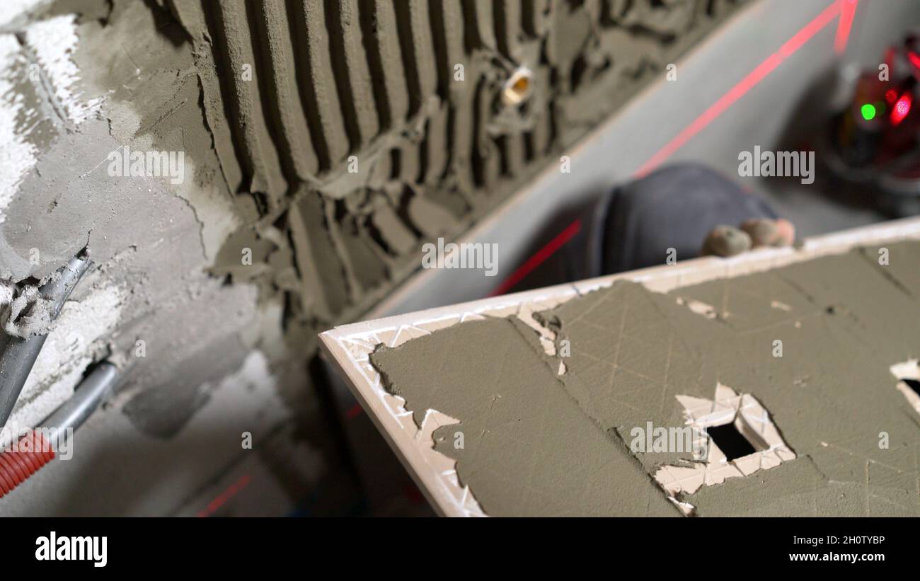 A worker smears ceramic tiles for laying. Laying ceramic tiles on the ...