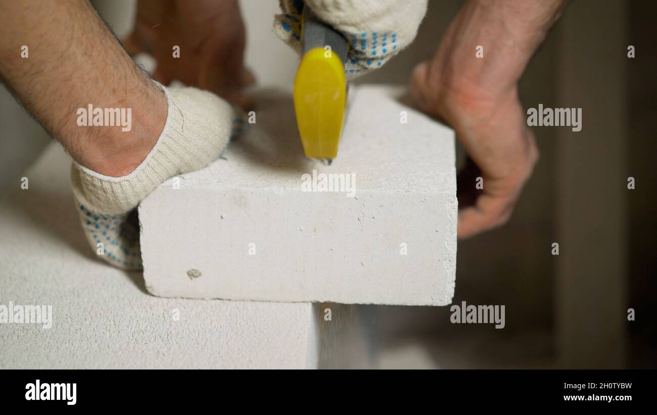 A worker cuts an aerated concrete block. Worker cutting construction ...