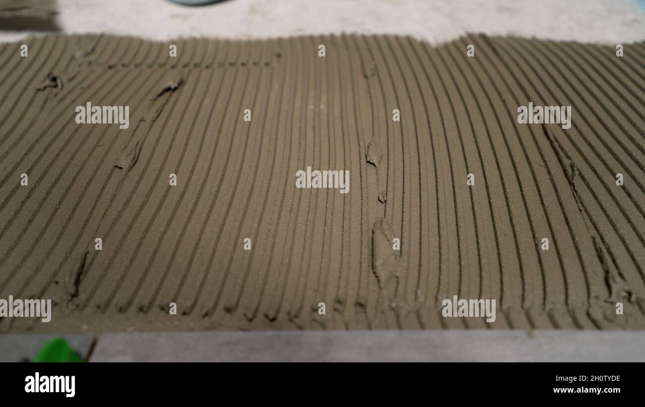 Tile adhesive applied to the floor for laying ceramic tiles. Dark grey ...