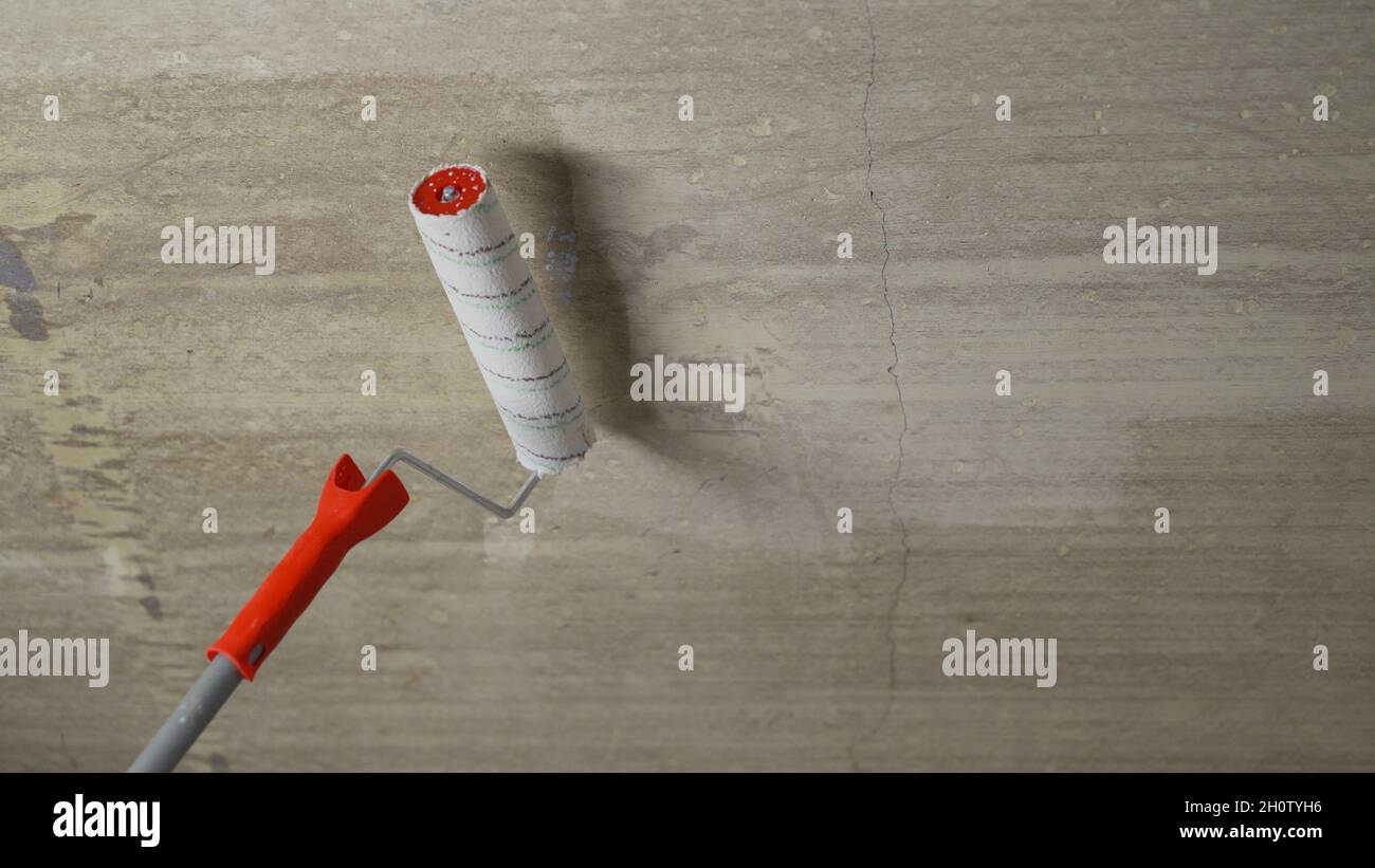 Priming the ceiling with a roller. Working primer with a ceiling paint ...