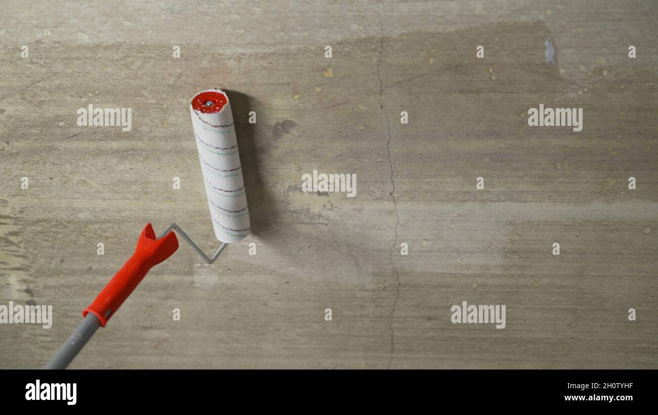 Priming the ceiling with a roller. Working primer with a ceiling paint ...