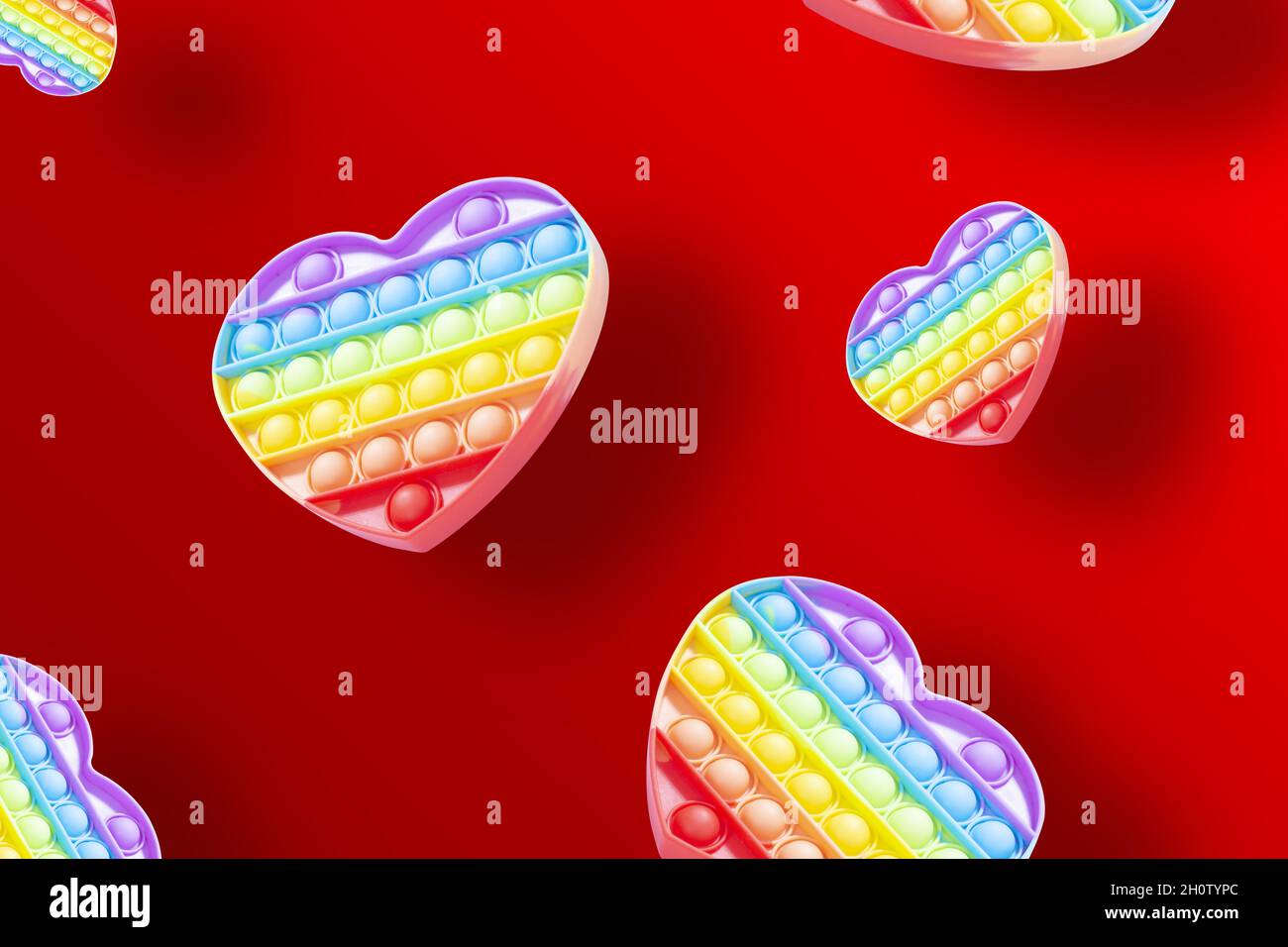 Bunch of rainbow-colored pop-it toys floating on a red background Stock ...