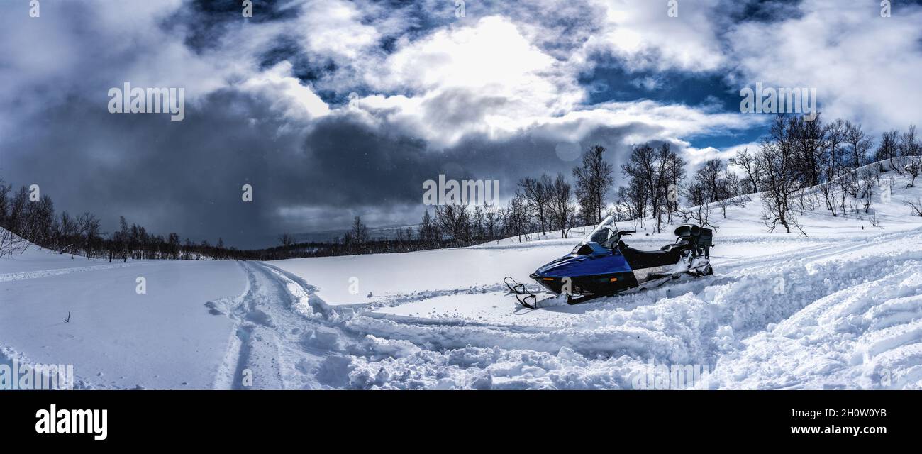 Scenic panorama view of snow mobile standing in deep snow at mountain ...