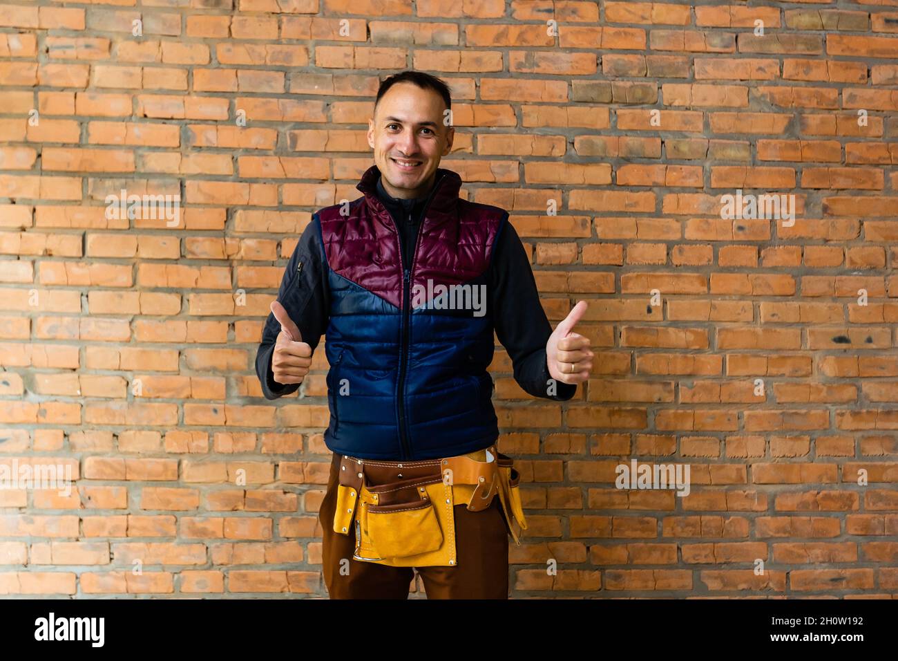 Closeup of bricklayer hands holding hardhat and construction equipment ...