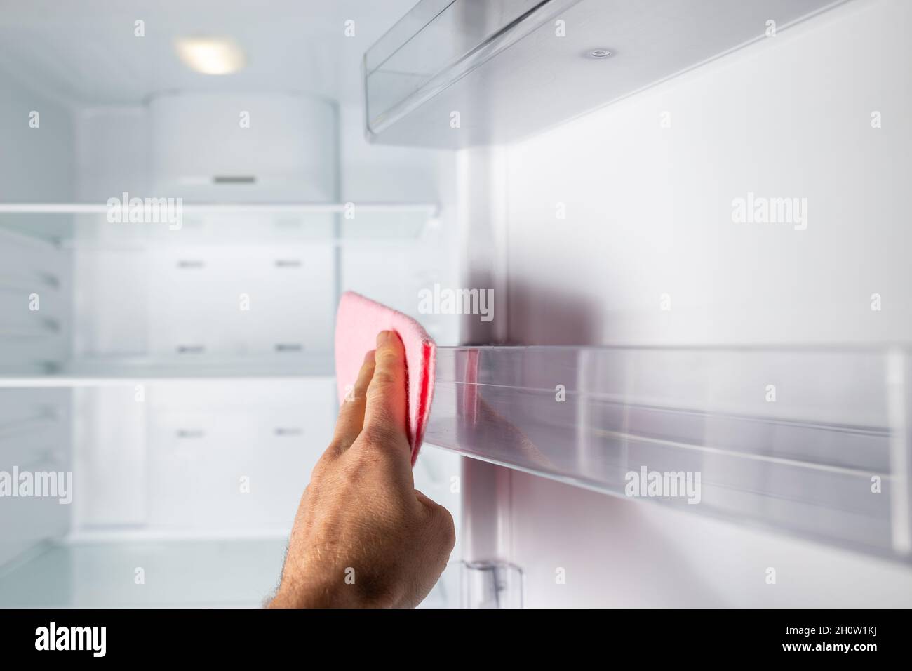 Hand cleaning empty fridge inside with piece of cloth Stock Photo - Alamy