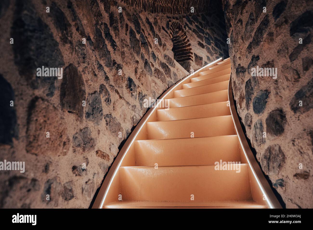 closeup perspective view of steep and narrow illuminated staircase ...