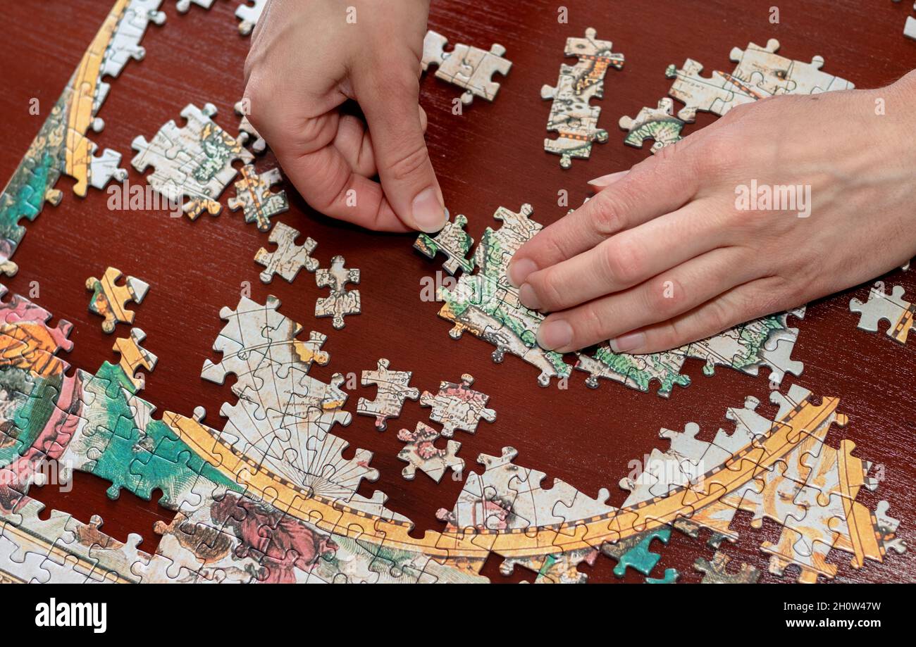 Hands putting jigsaw puzzle pieces together. Home alone. Quarantine in ...