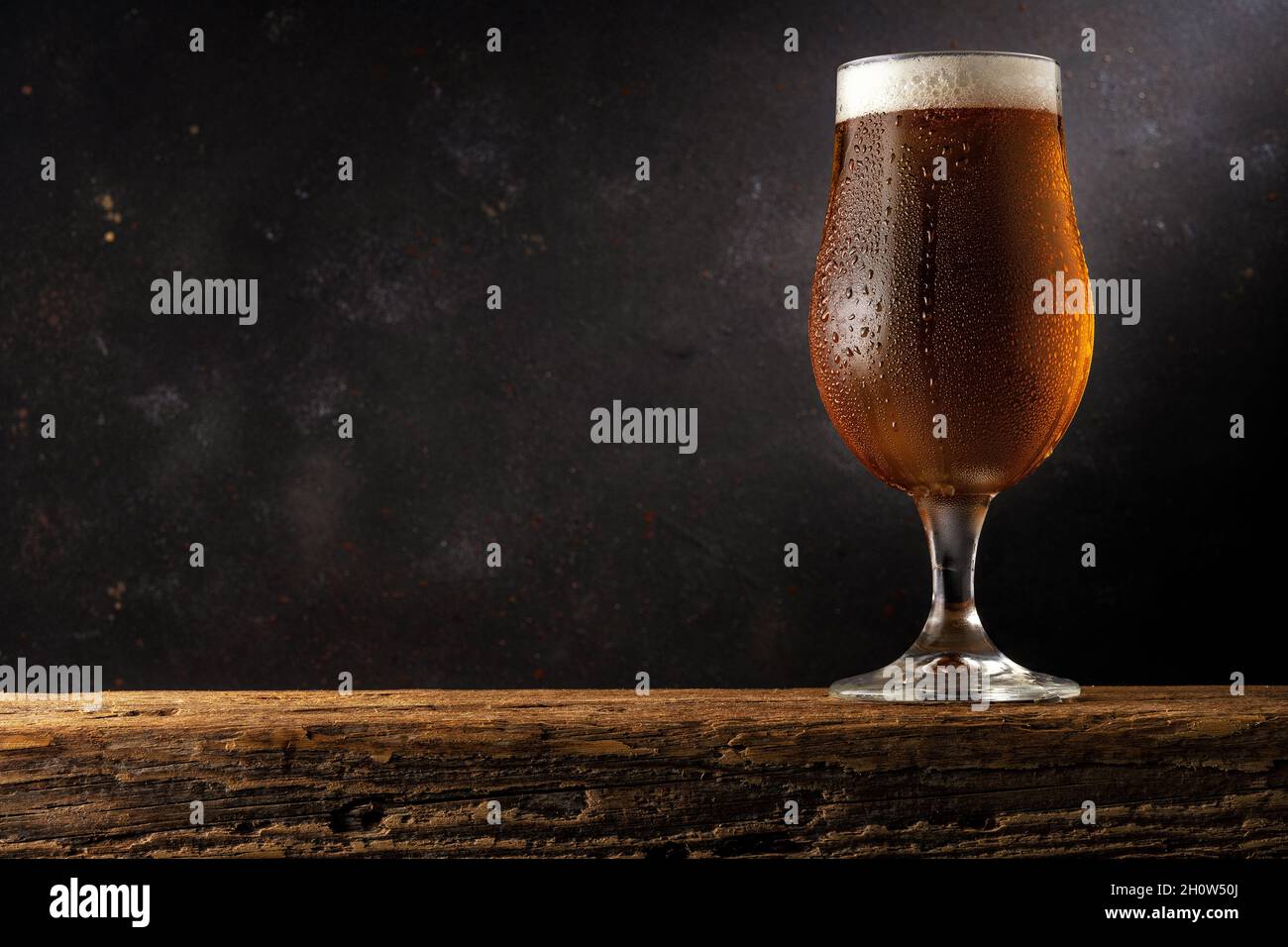 Glass of light beer on a wooden table. Dark background. Drink concept ...