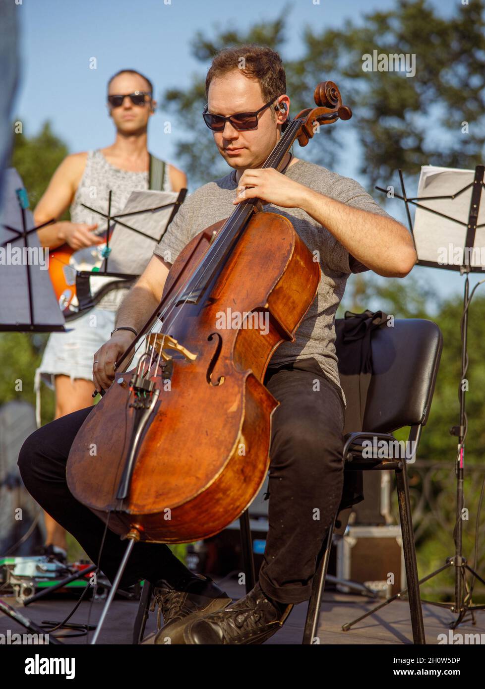 Male violoncellist playing cello in orchestra outdoors Stock Photo - Alamy