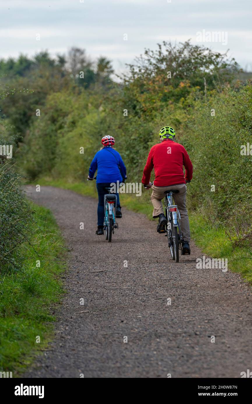 middle-aged older couple riding bicycles along a country lane on the ...