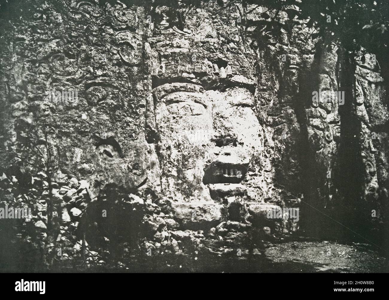 Giant sculpture of a face on the base of a pyramid at the Mayan ruins ...