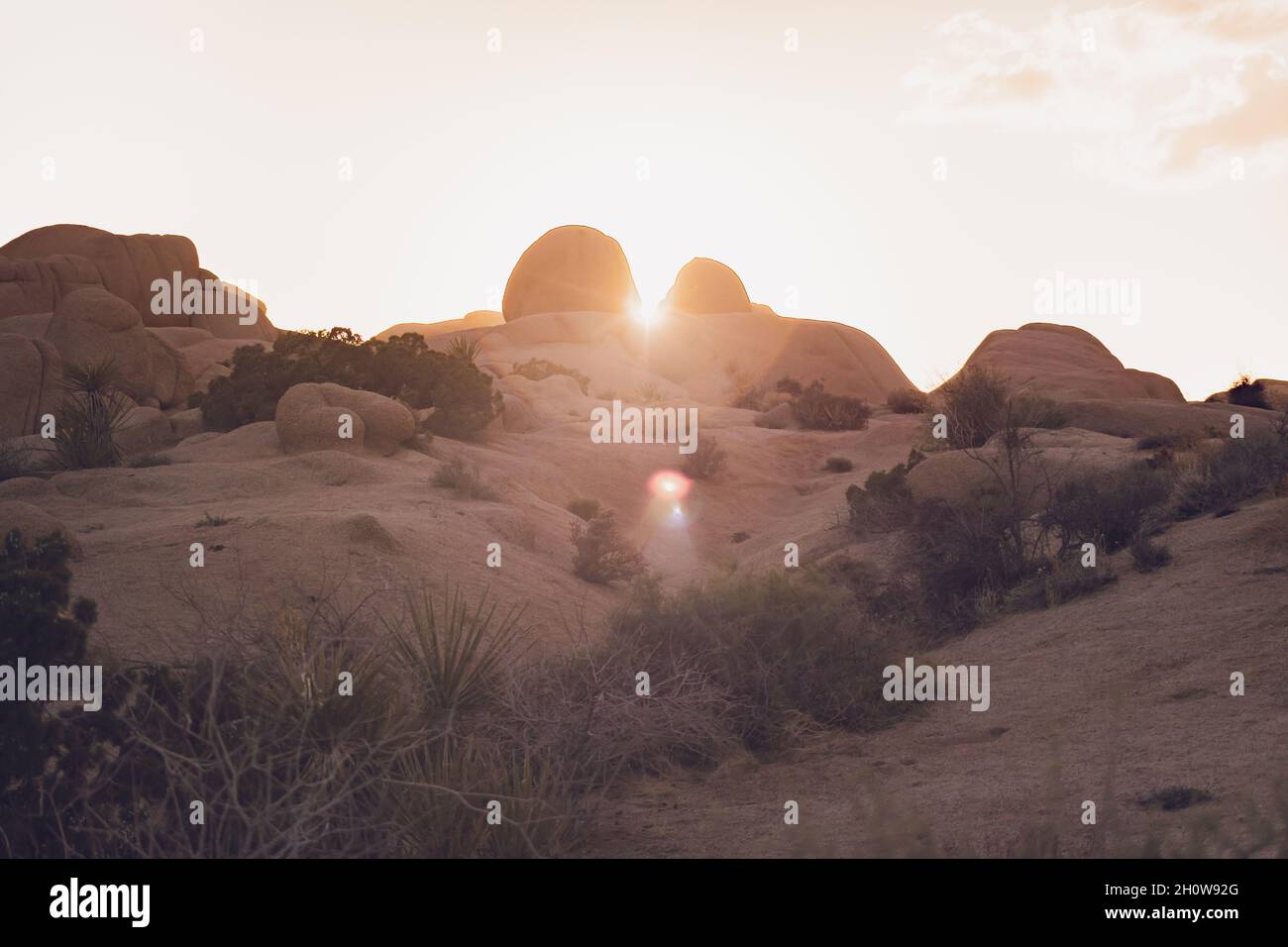 Sun shining through big rocks in the desert Stock Photo - Alamy