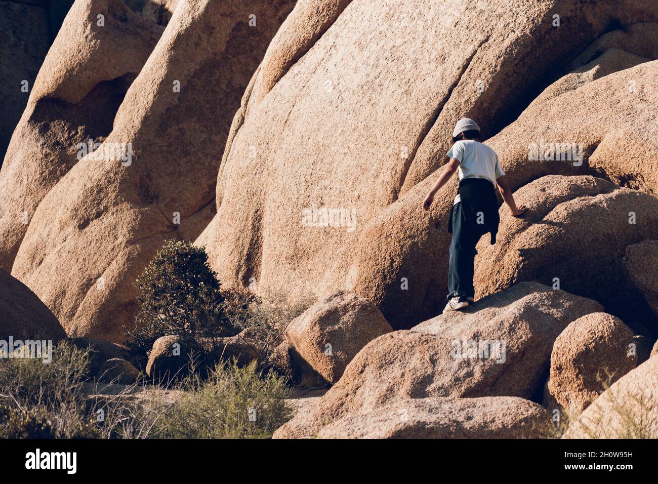 Older boy walking among big rocks in the desert Stock Photo - Alamy