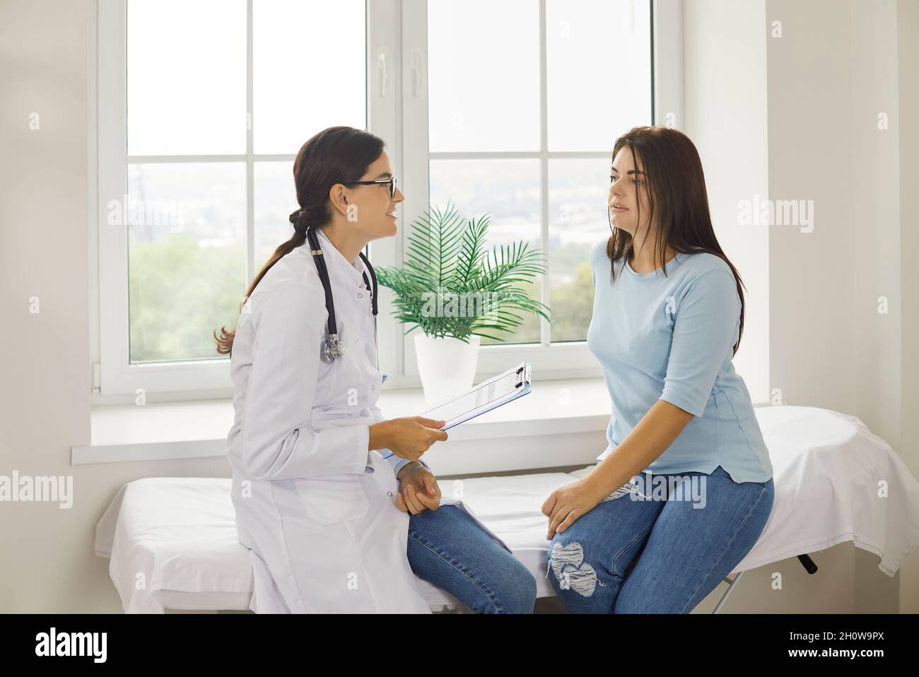 Young woman talks to her female doctor during a medical examination at ...