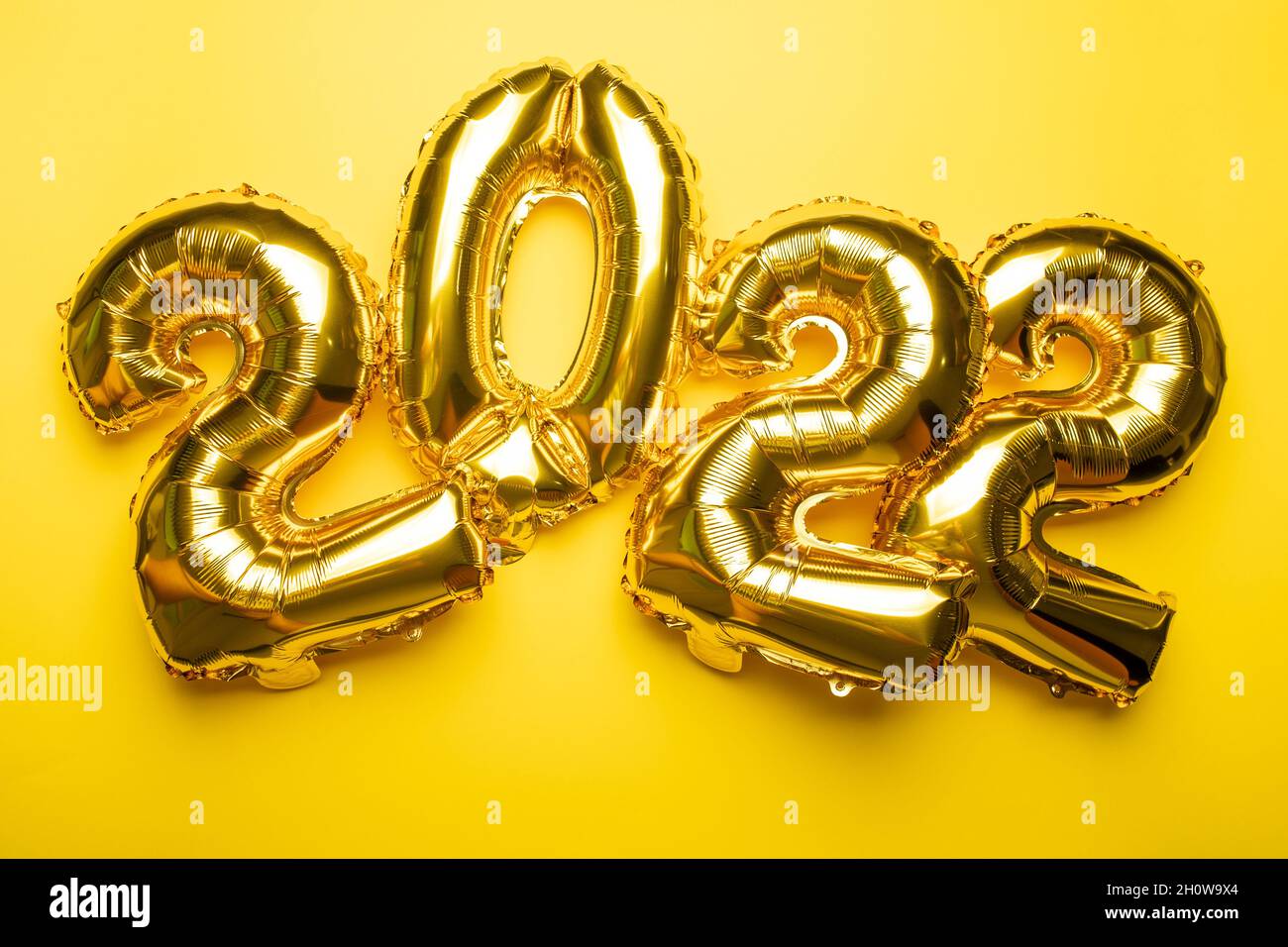 2022 Concept New Year from golden foil balloon on yellow background ...
