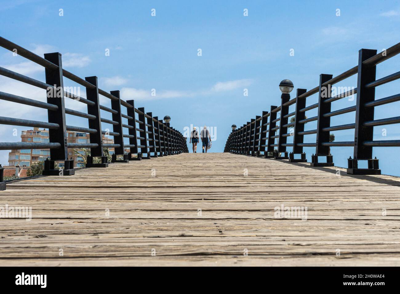 two people walking on a wooden and metal bridge Stock Photo - Alamy