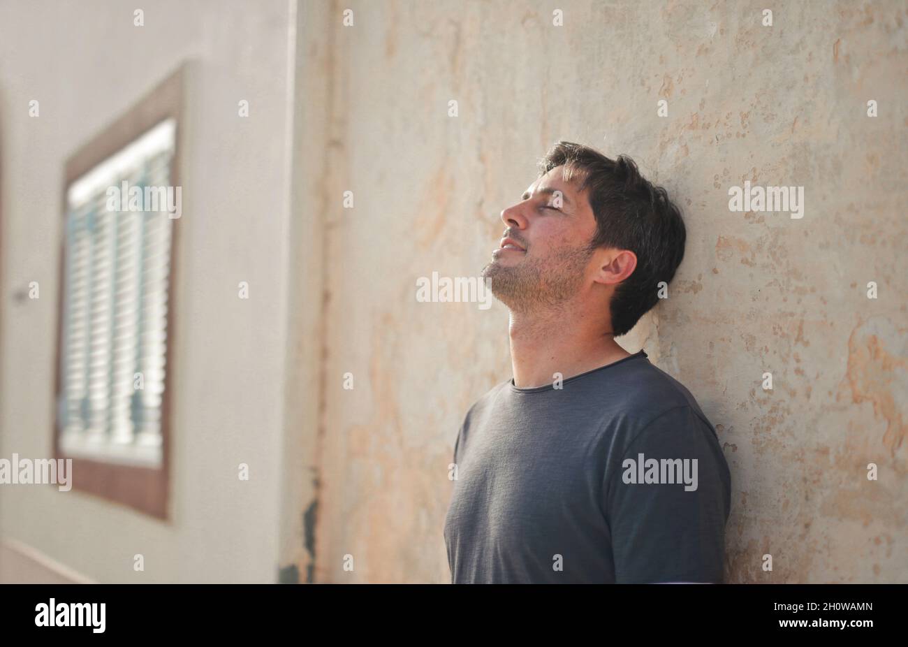 portrait of young man leaning against a wall Stock Photo - Alamy