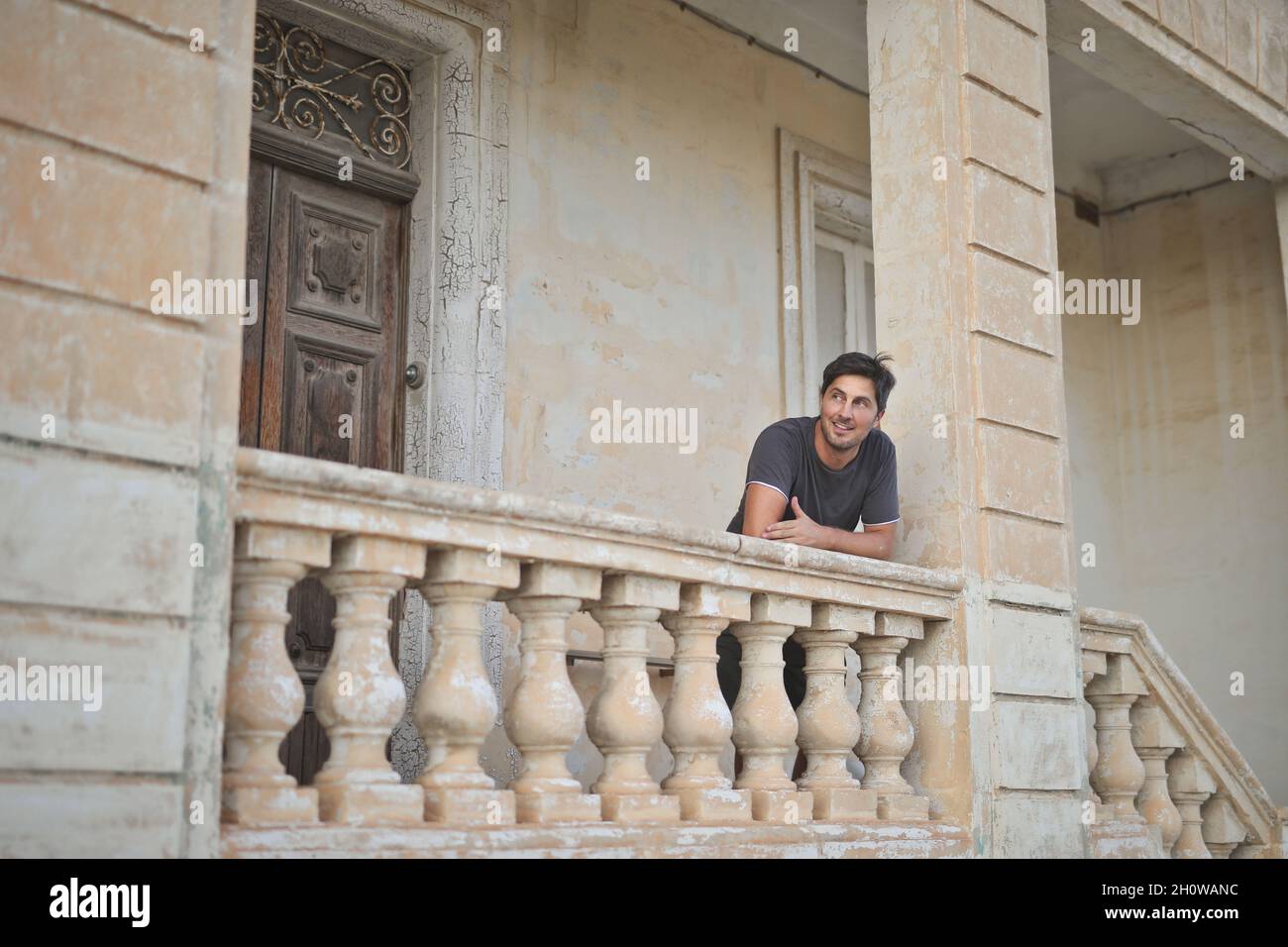 portrait of young man waiting for someone on the entrance of the house ...