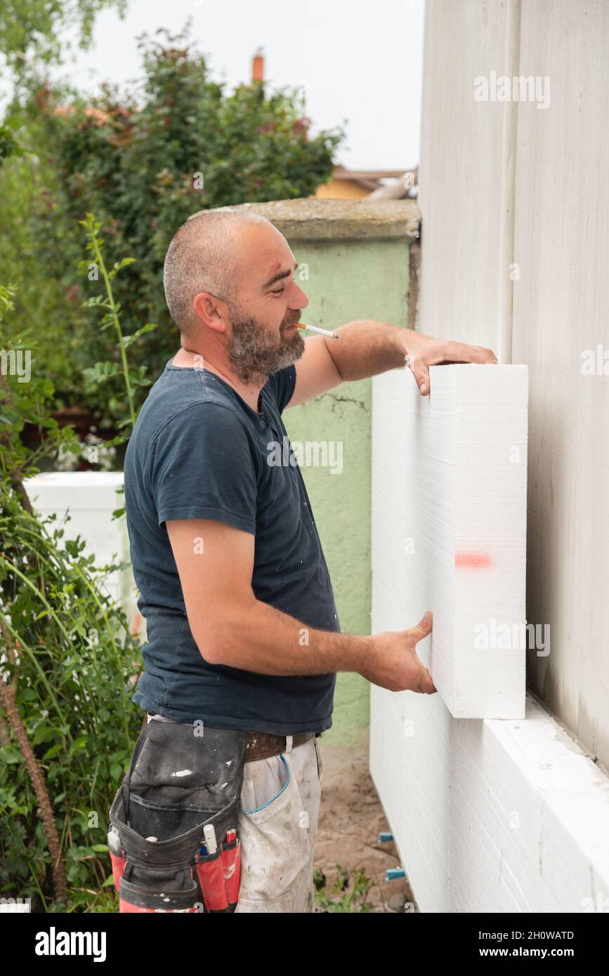 Construction worker gluing block on the wall of house Stock Photo - Alamy