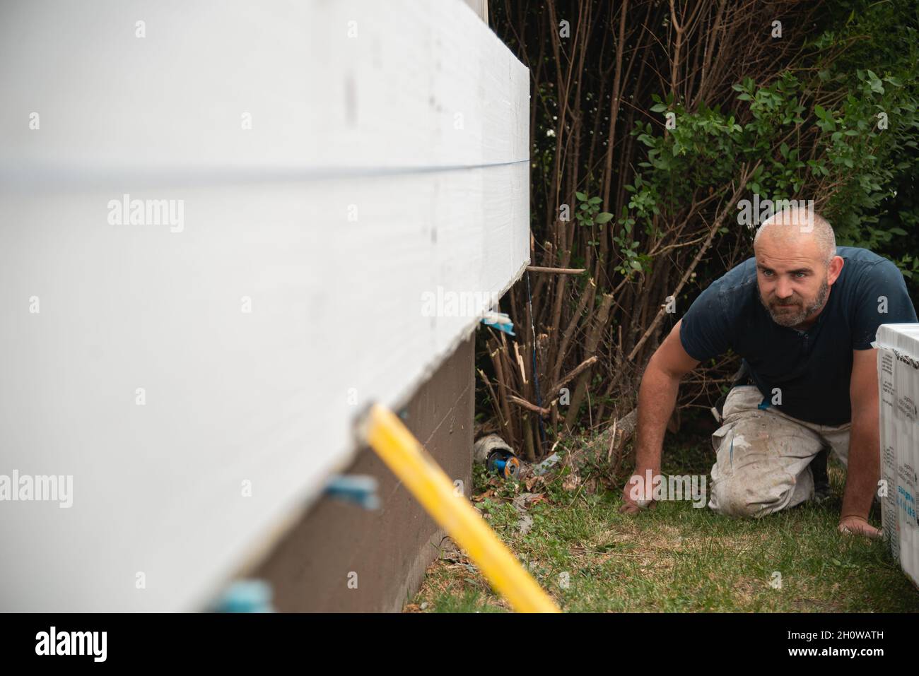 Construction worker checking straightness of glued isolation boards ...