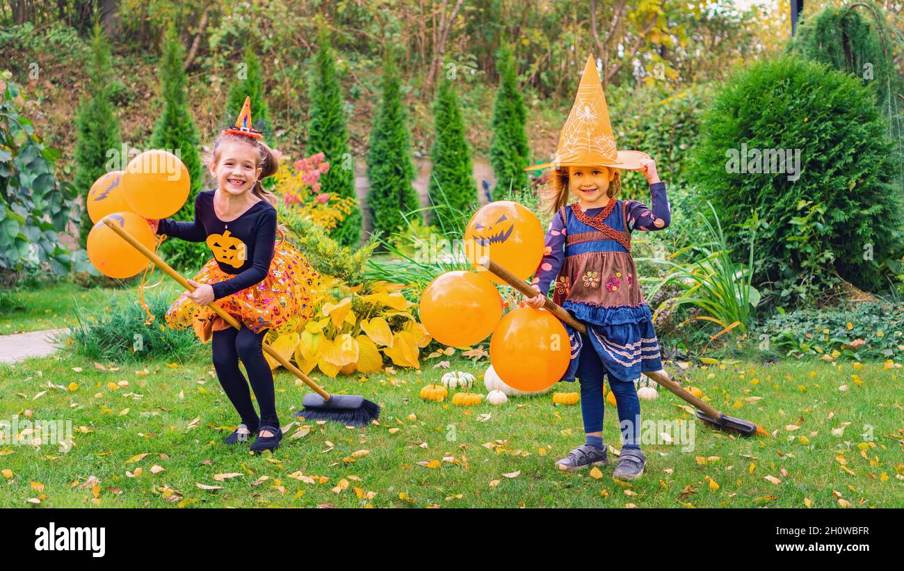 Little witches learn to fly broomsticks at an outdoor Halloween party ...