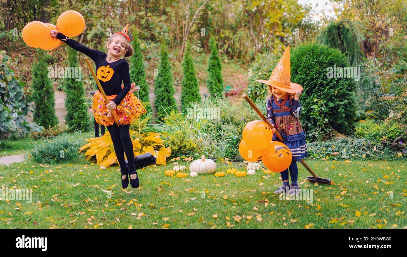 Children in witch hats laugh and play with brooms. Little witches learn ...
