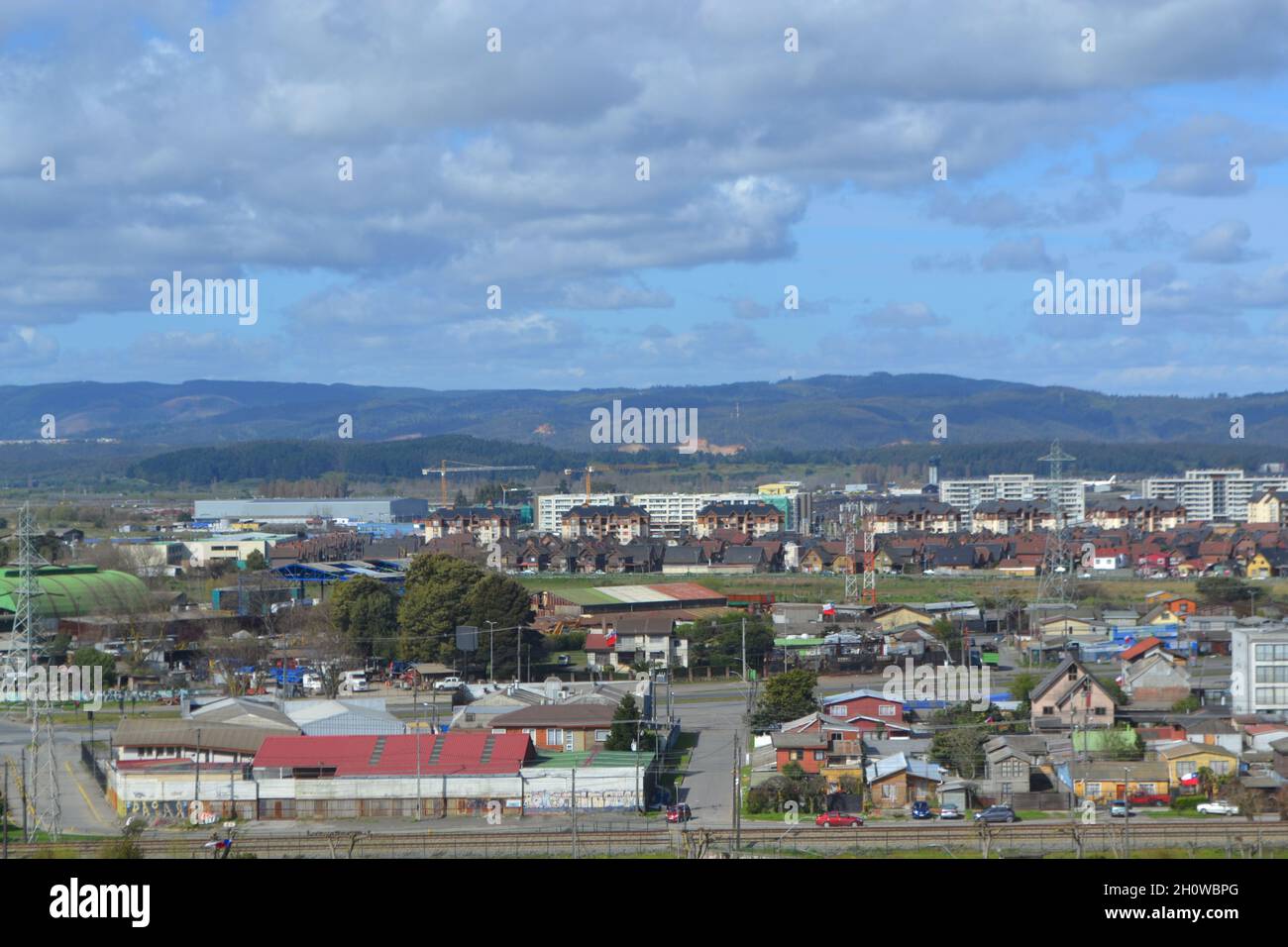 Beautiful scene of a town surrounded by mountains and trees on a cloudy ...