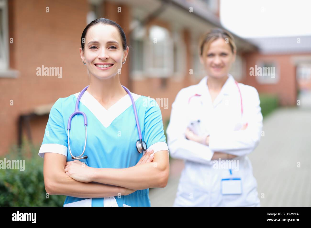 Two smiling female doctors stand with folded arms Stock Photo - Alamy