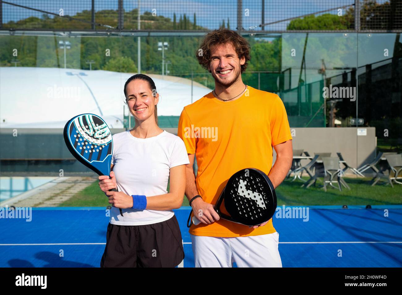 Portrait of two smiling sportsman's posing on padel court outdoor with ...
