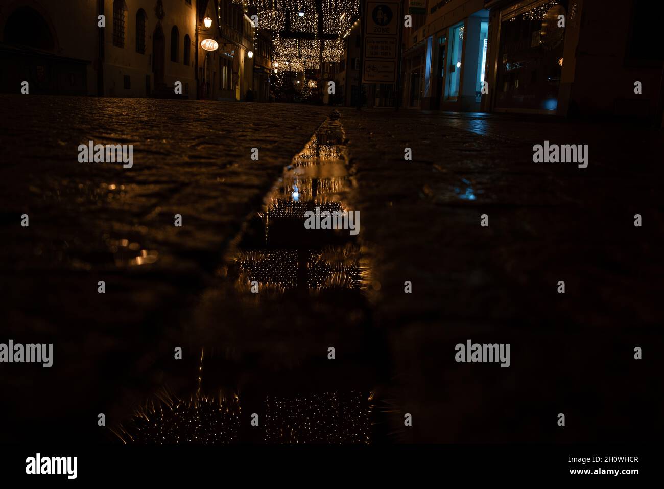 Closeup of lights on buildings reflecting on water on the ground at ...