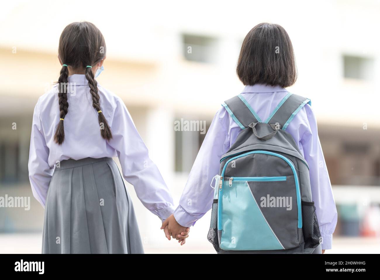 Shallow focus of two adorable kids in school uniforms holding hands and ... Shallow focus of two adorable kids in school uniforms holding hands and ...