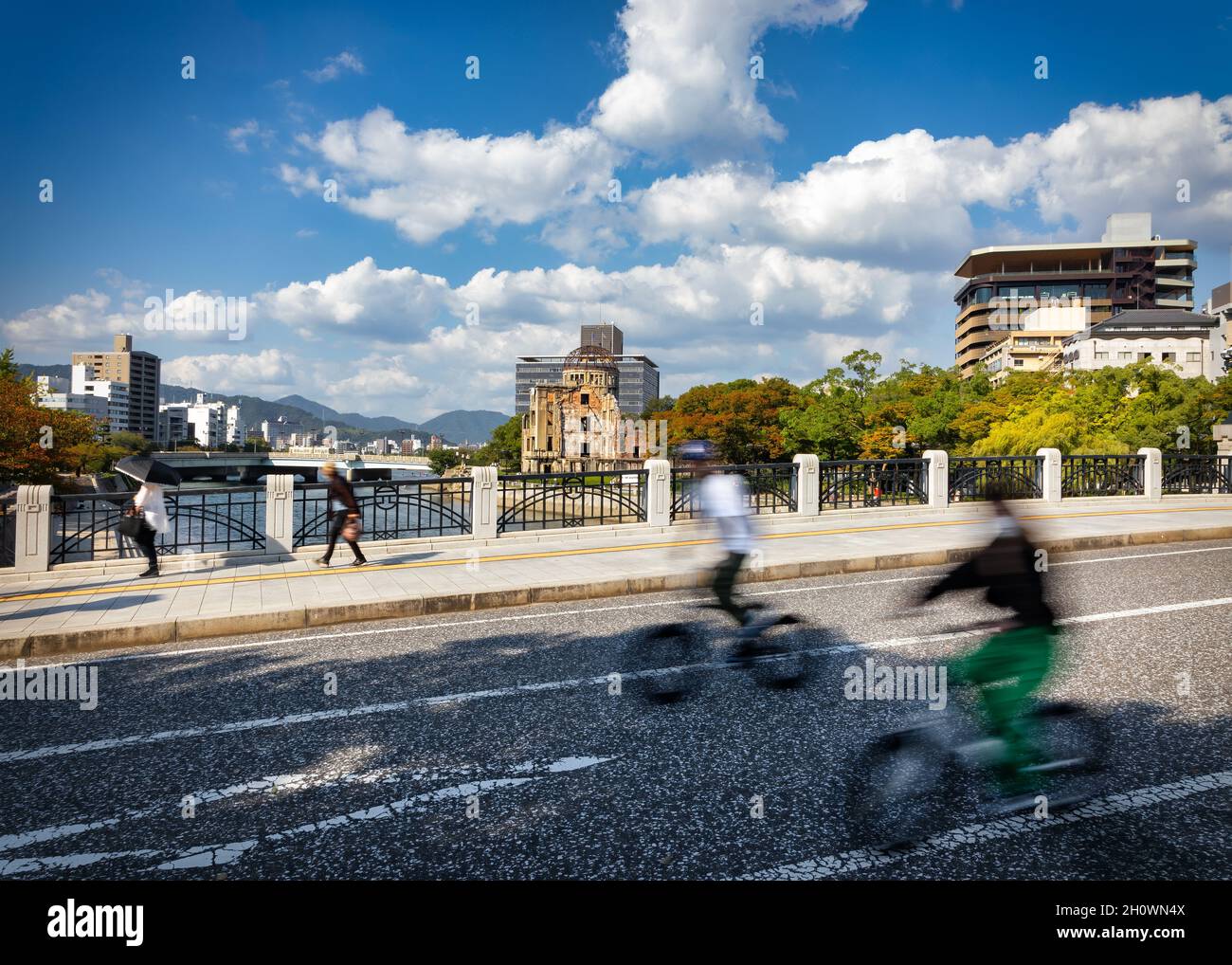 Bicylists and pedestrians cross the Motoyasu River Bridge passing the ...