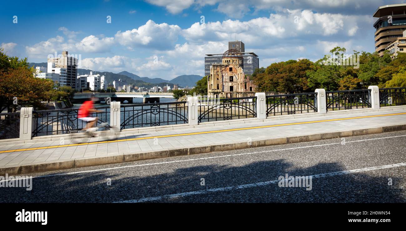 A bicylists crosses the Motoyasu River Bridge passing the ruins of the ...