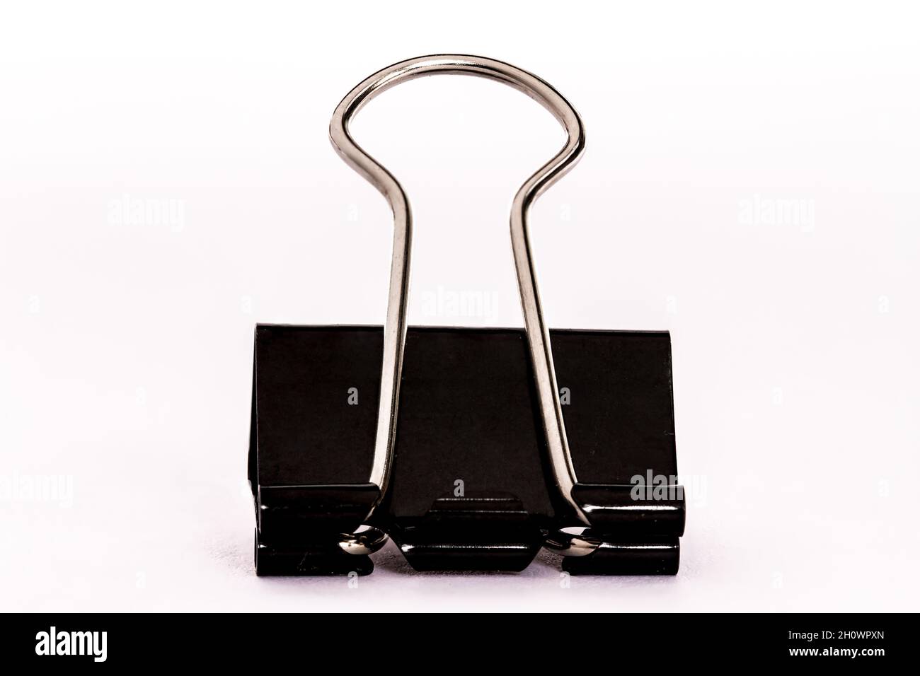 One black paper clip made of metal, isolated with a white background ...