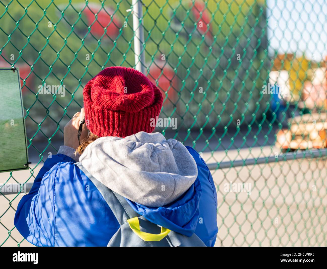 A woman looking through the wire fence net. Street view, travel photo ...