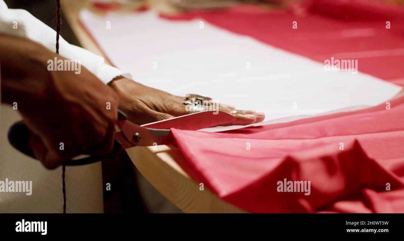 A woman is cutting fabric with a scissors Stock Photo - Alamy