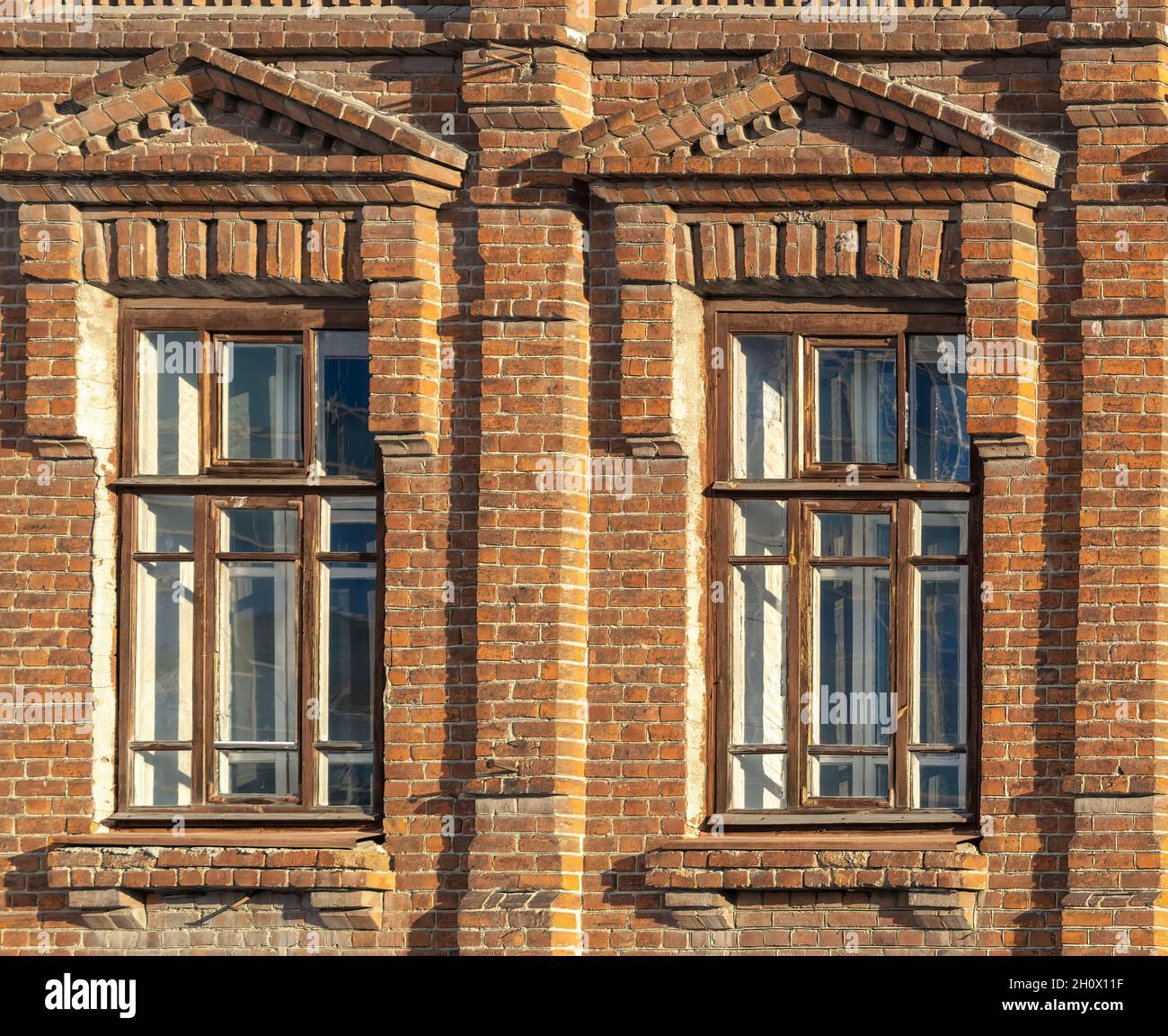 Two windows of the old mansion 19 century with brown bricks wall. Brick ...
