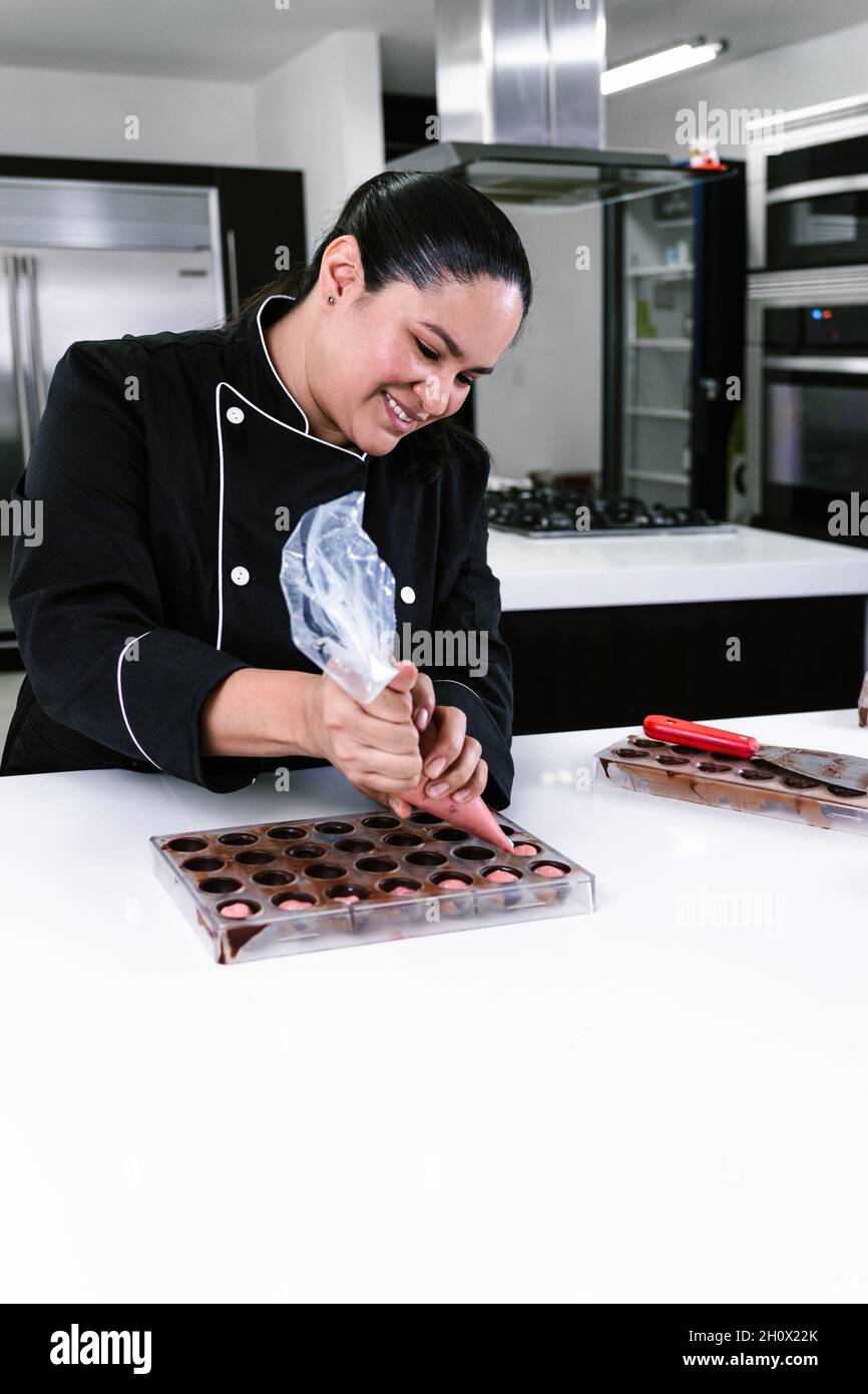 latin woman pastry chef wearing black uniform in process of preparing ...