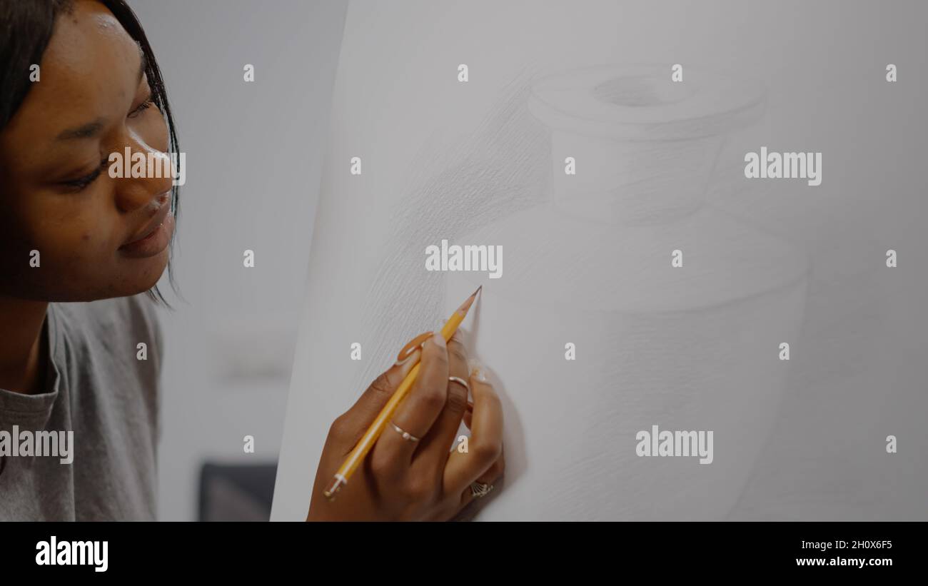 Close up of black hand with pencil drawing on white canvas and wooden ...